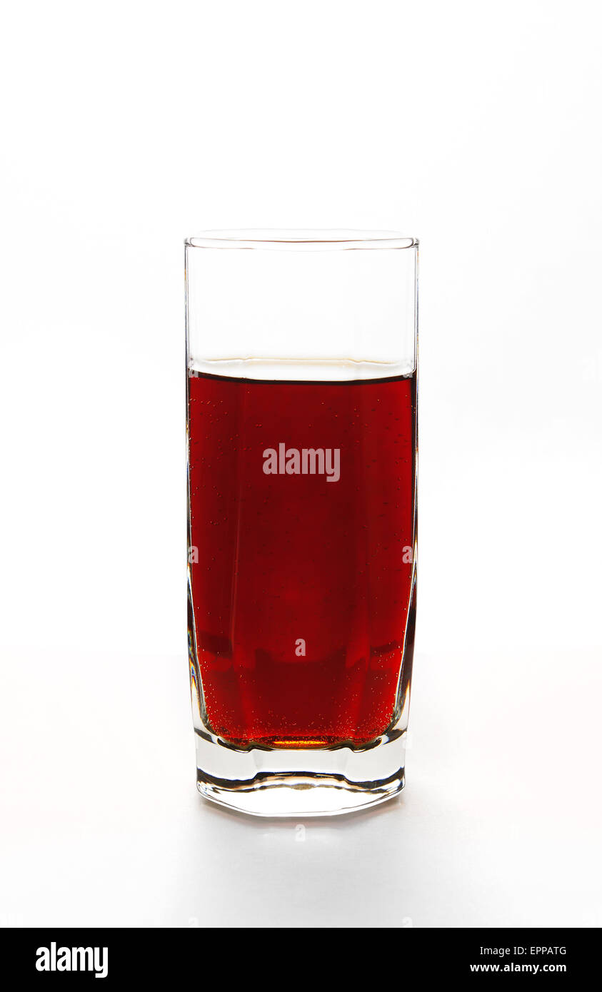refreshing drink of red color in a tall glass on a white background ...