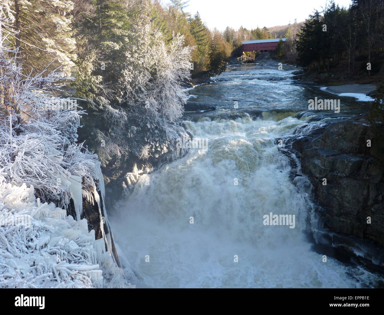Covered bridge and a waterfall in winter at Quebec, Canada Stock Photo ...