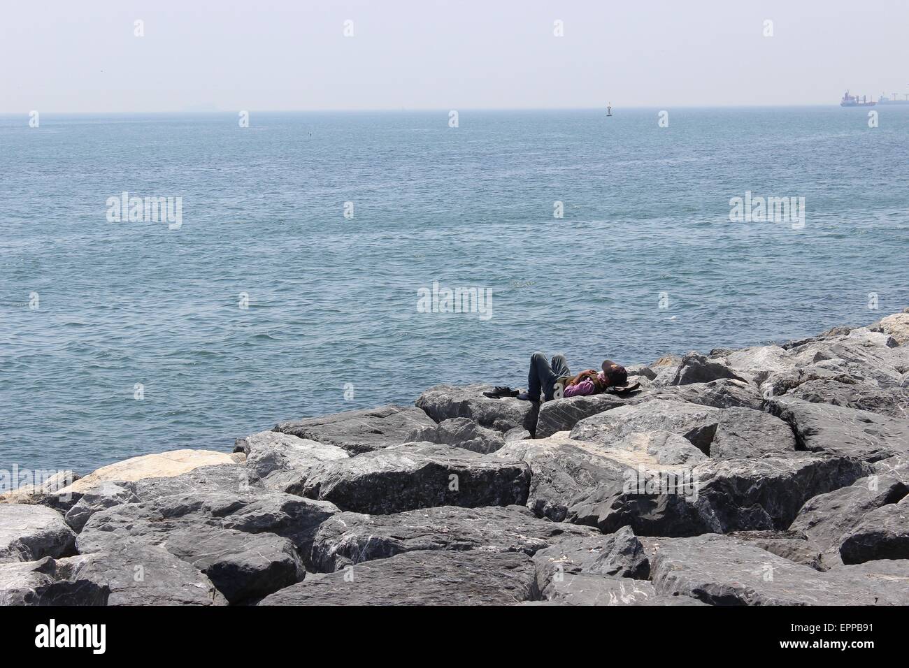Man sleeping on the rocks near the sea (on the seawall Stock Photo - Alamy