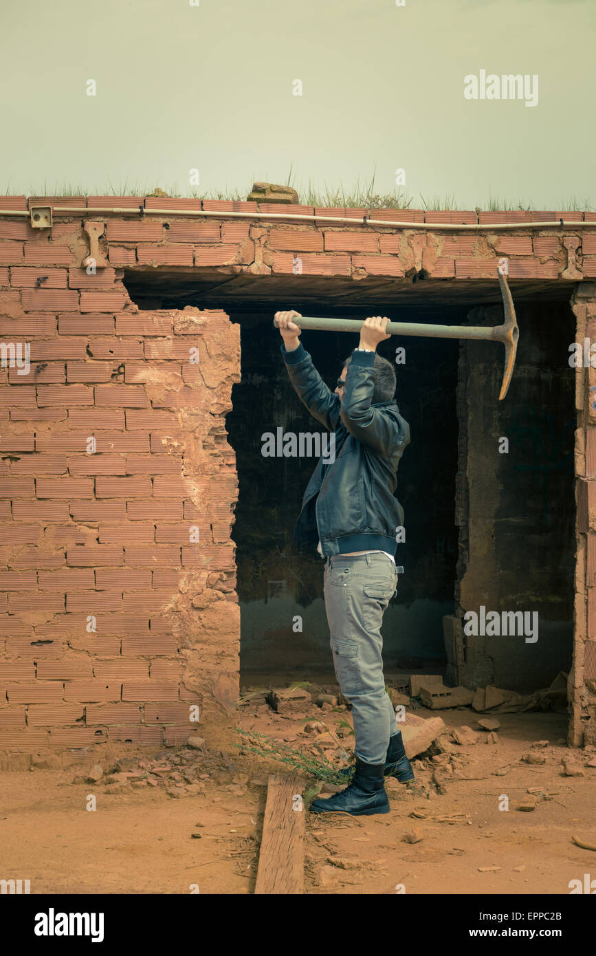 Guy knocking down a wall using a pickaxe Stock Photo - Alamy