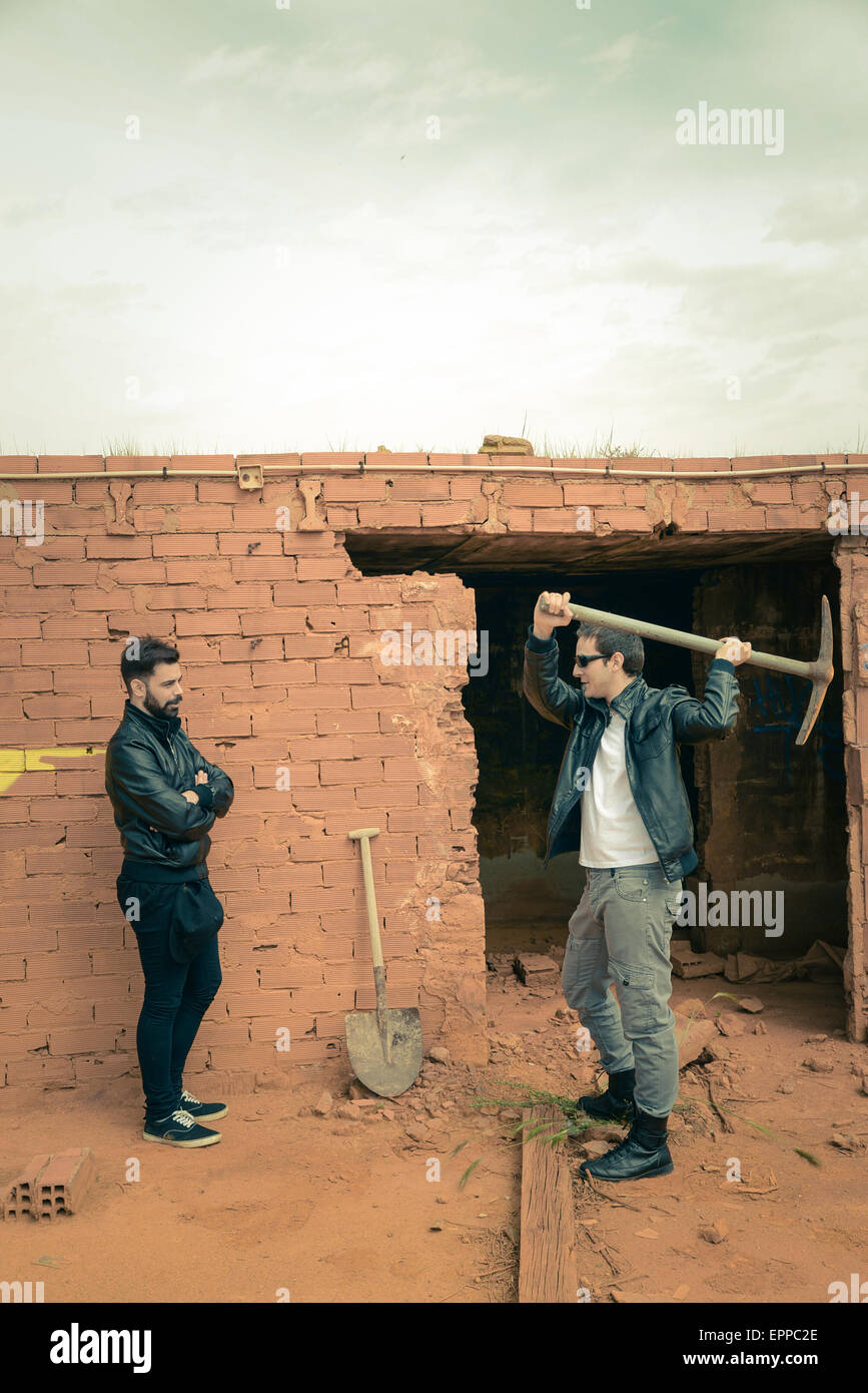 Guy pulling down a wall while another one is watching Stock Photo - Alamy