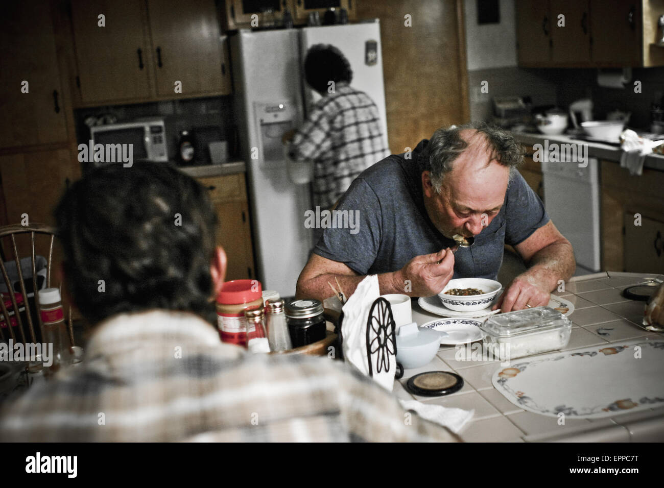 A father and son eat dinner at the kitchen table after milking the cows ...