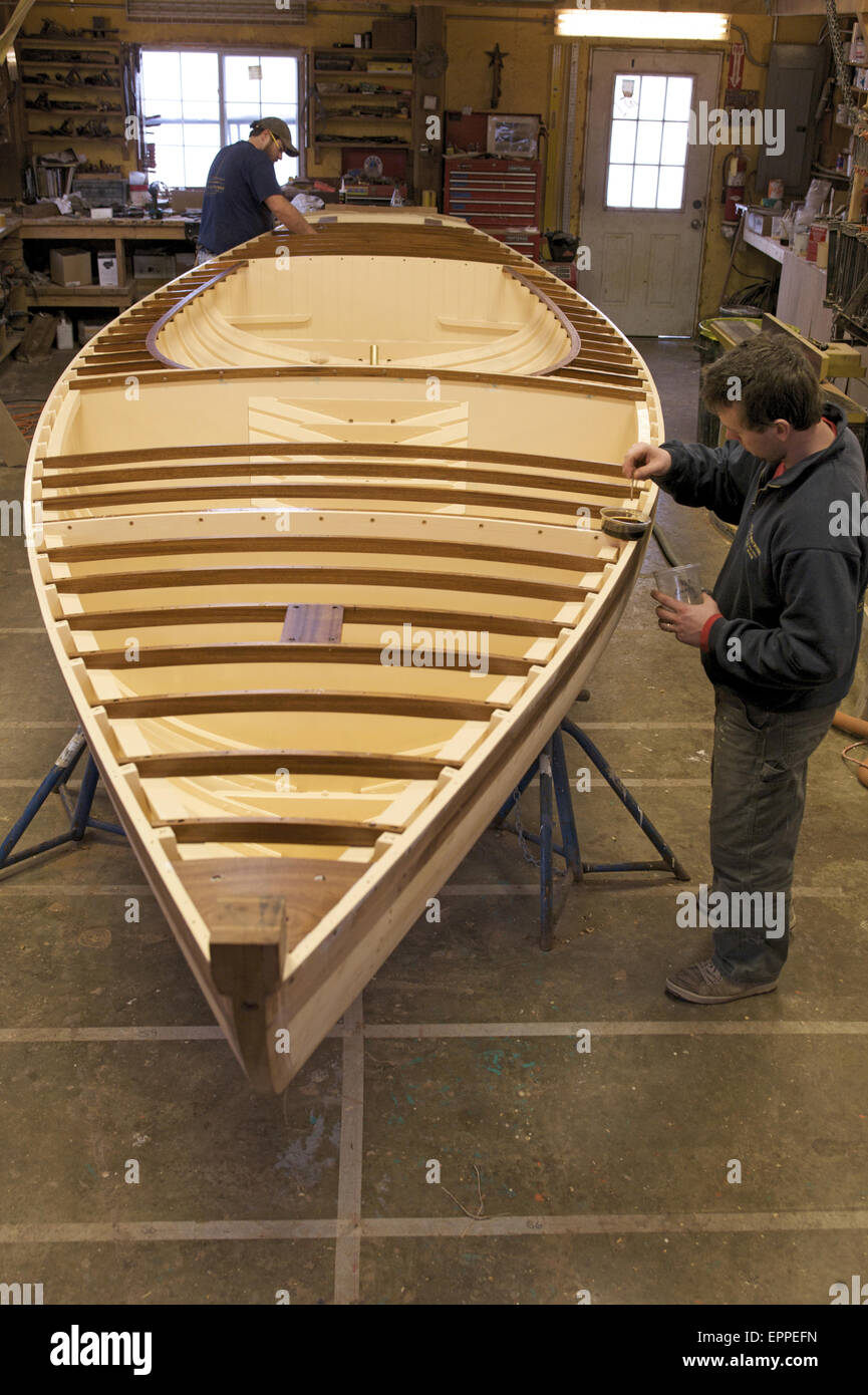 A boat builder, works on the boat he is restoring in a boatbuilding ...
