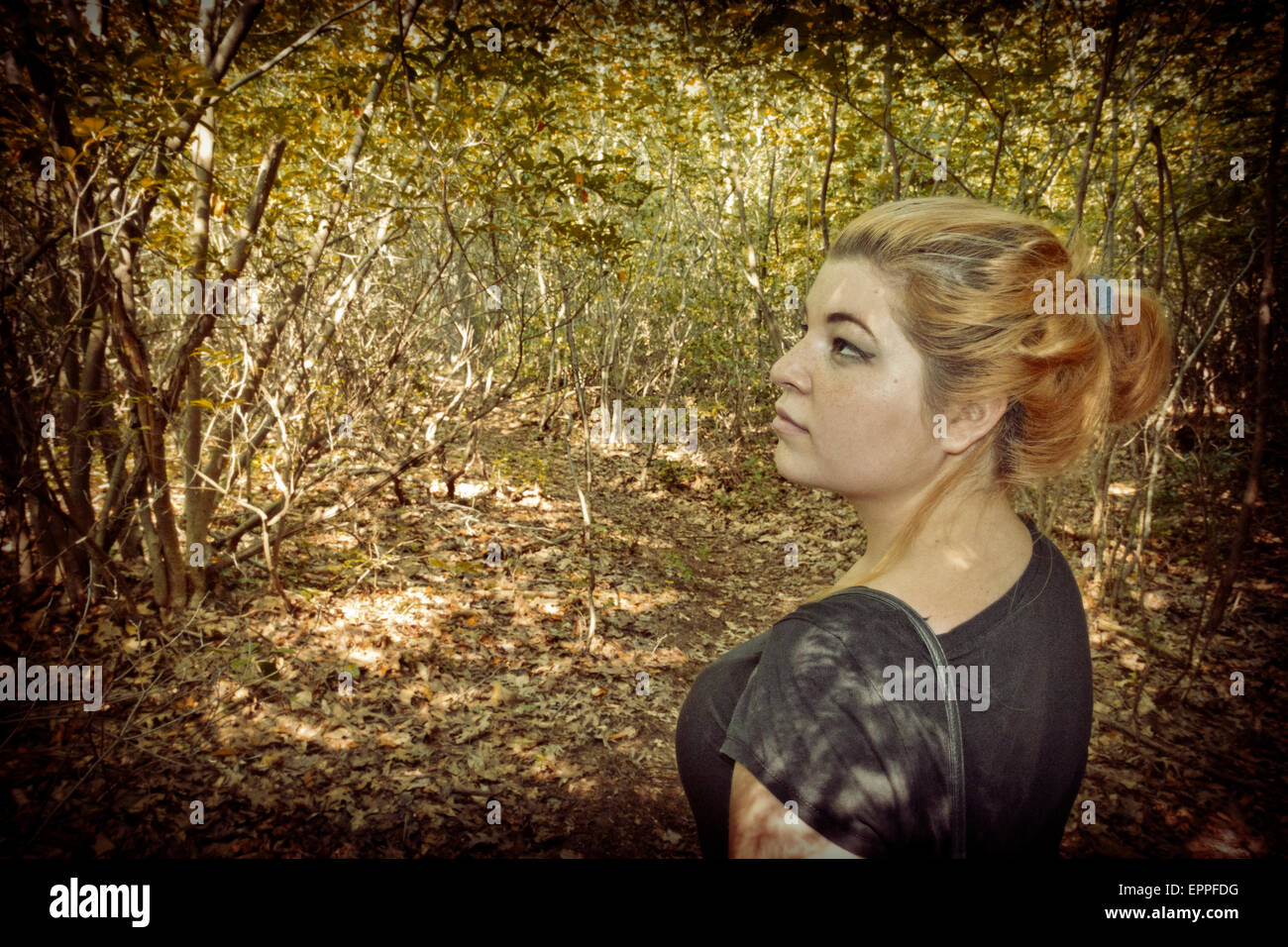 A girl gazes into the thick forest brush, deep in thought Stock Photo ...