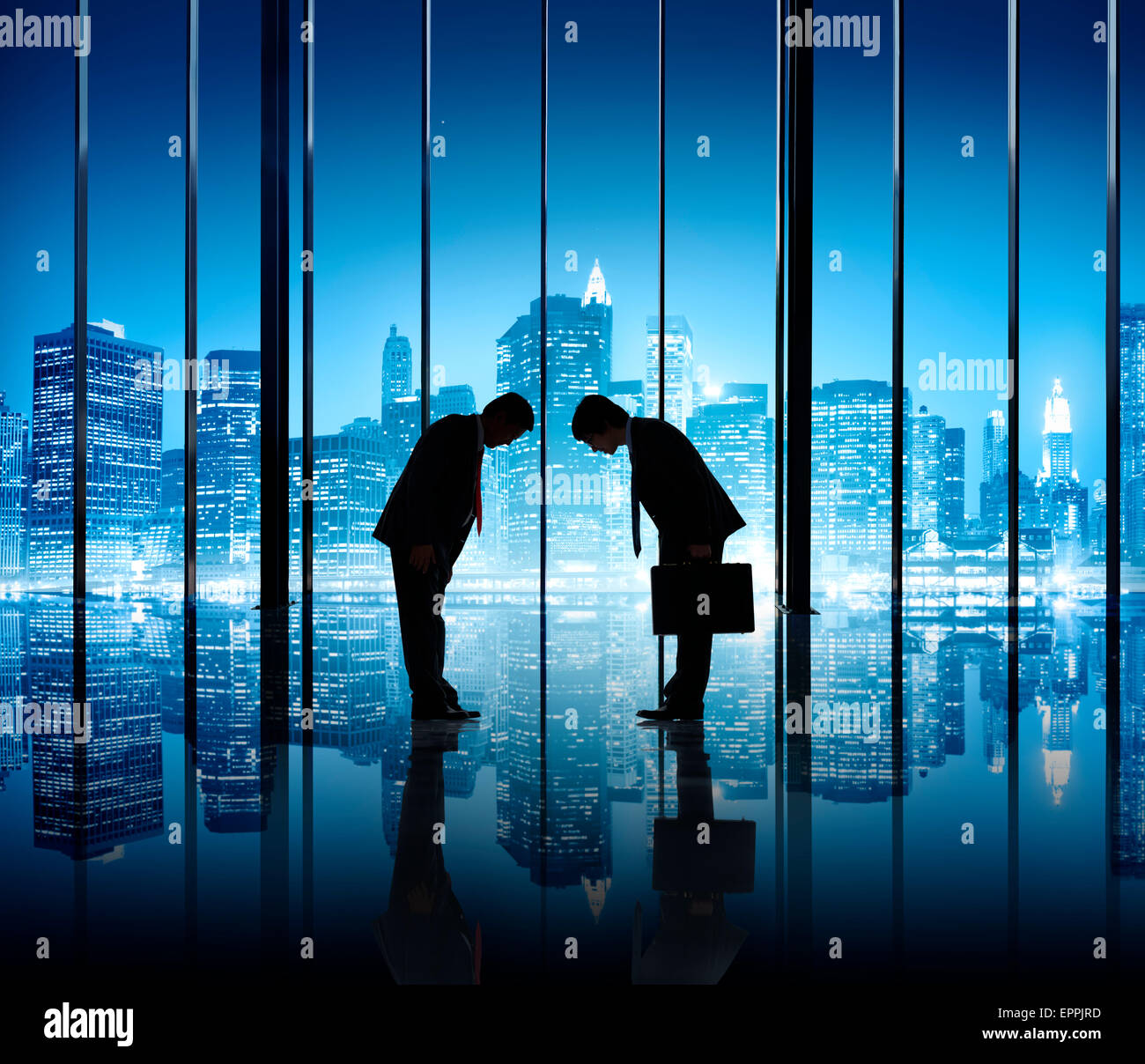Two businessmen bowing to each other in an office building Stock Photo ...