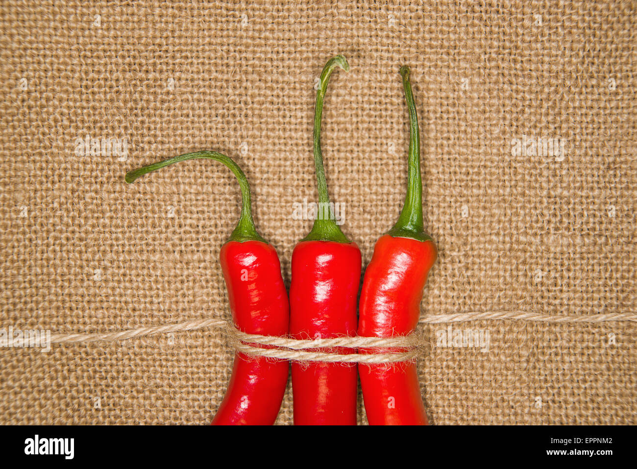 Three Chile peppers tied with a rope on old cloth Stock Photo - Alamy