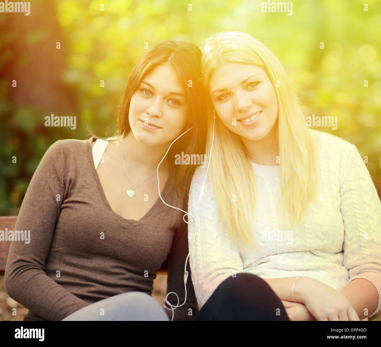 Two teenage girls listening to music outdoors Stock Photo - Alamy