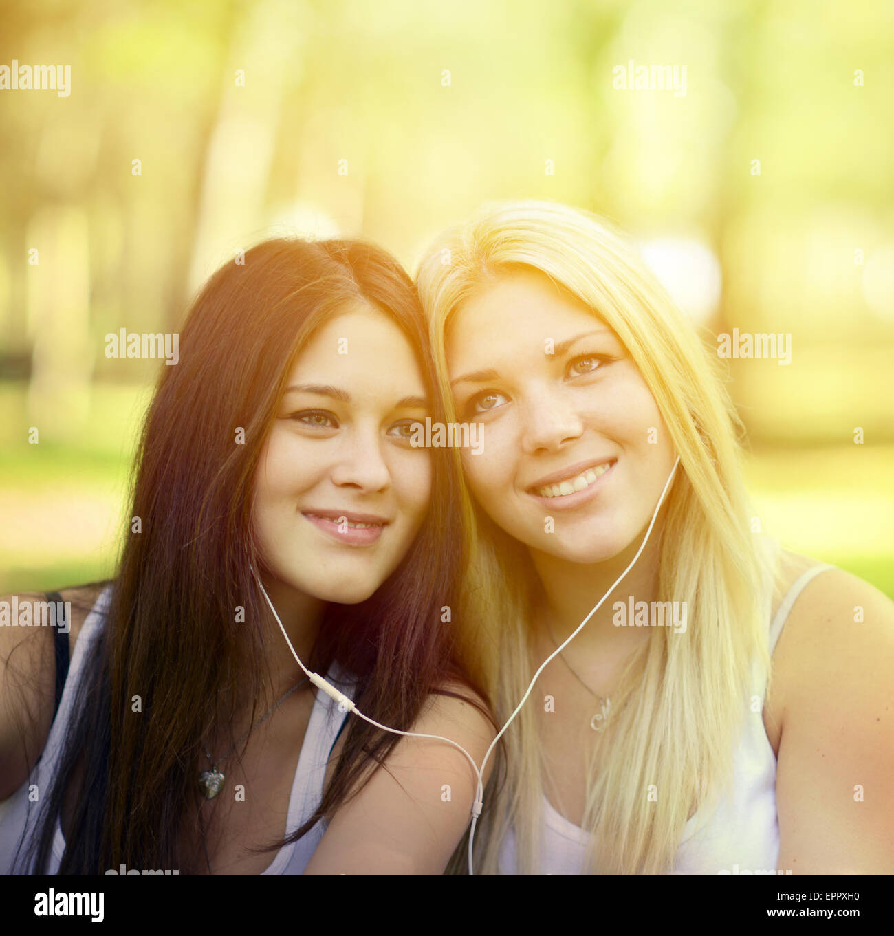 Two teenage girls listening to music outdoors Stock Photo - Alamy