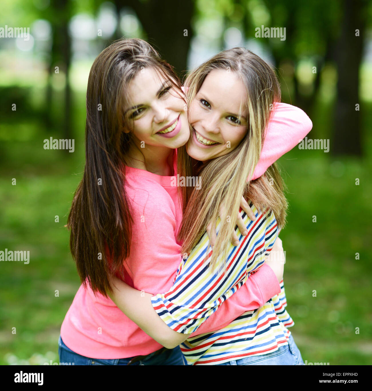 Two young girl friends in a hug at park Stock Photo - Alamy