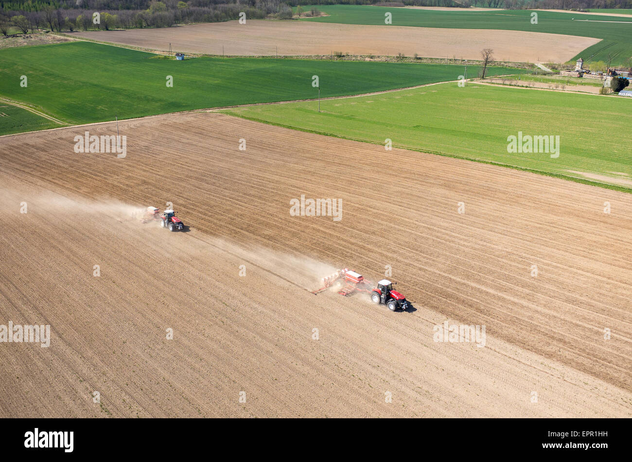 Aerial view of the tractor harrowing the large brown field in spring ...