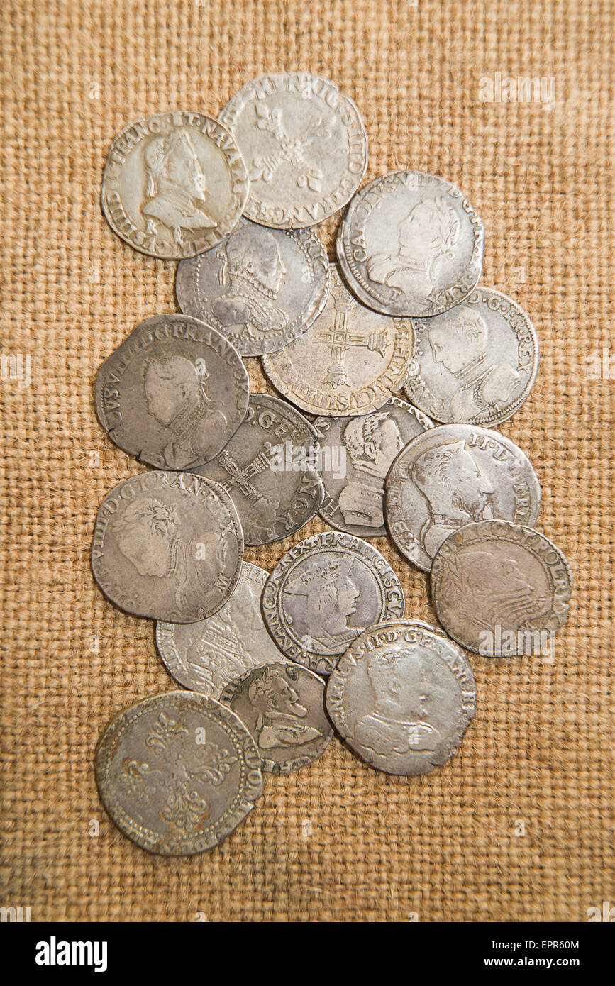 A lot of old silver coins with portraits of kings on the old cloth ...