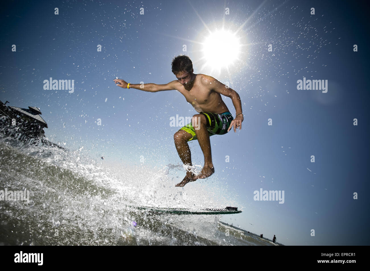 A teenage boy jumps over shallow waves on a skim board Stock Photo - Alamy