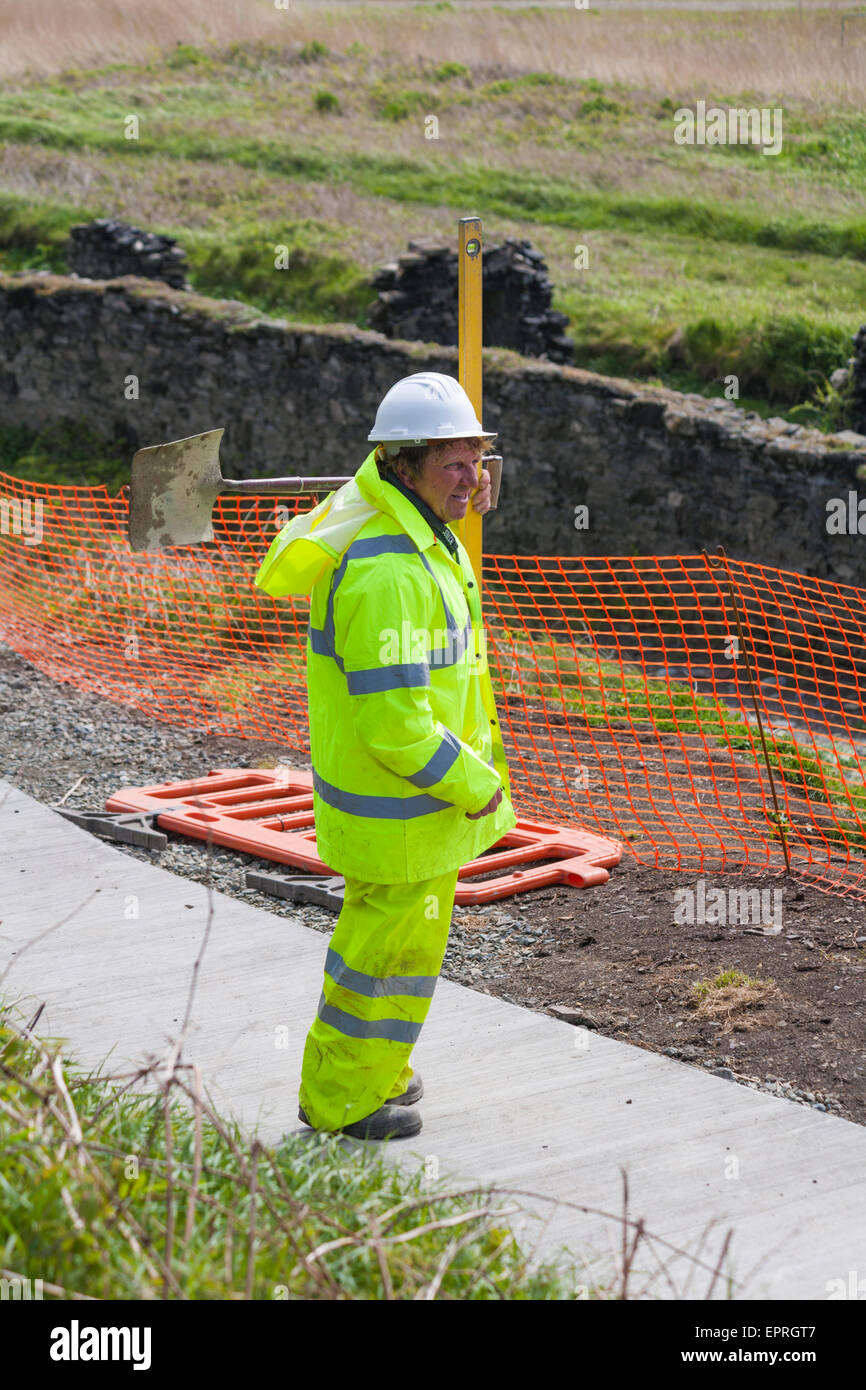 Workman carrying shovel and spirit level - workmen laying new path at ...