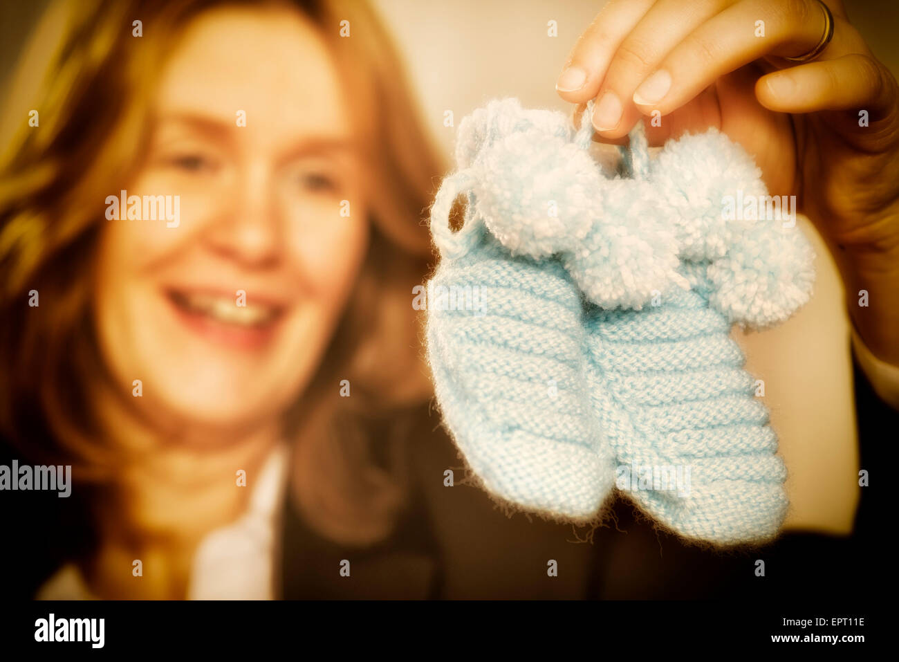 Blond woman is holding two blue baby shoes Stock Photo - Alamy