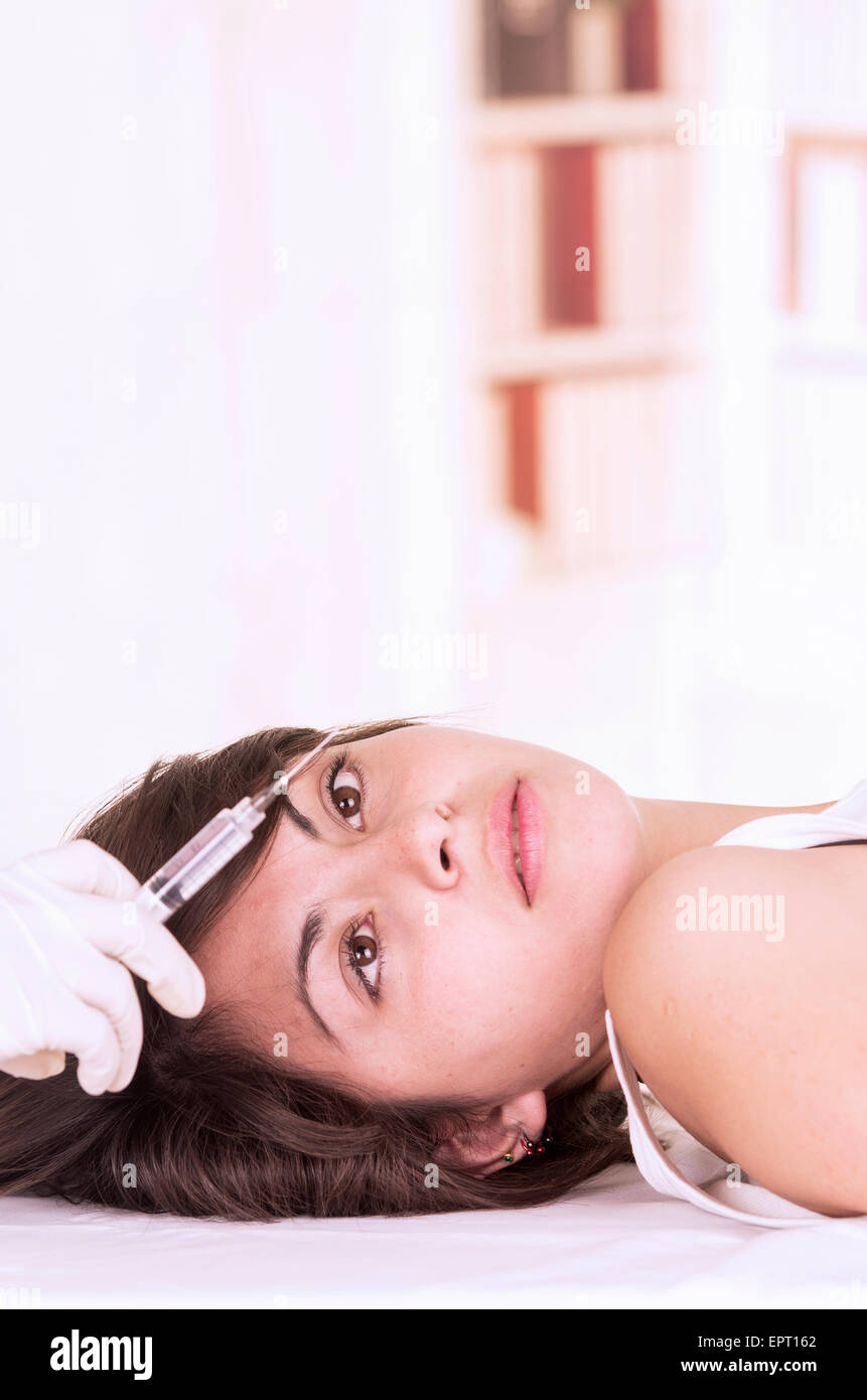 Young girl lying down ready to get a cosmetic injection in her face ...