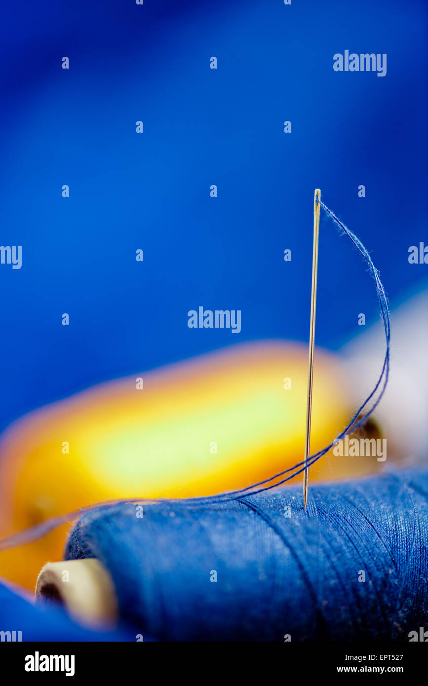 needle and blue and yellow thread on the blue background Stock Photo - Alamy