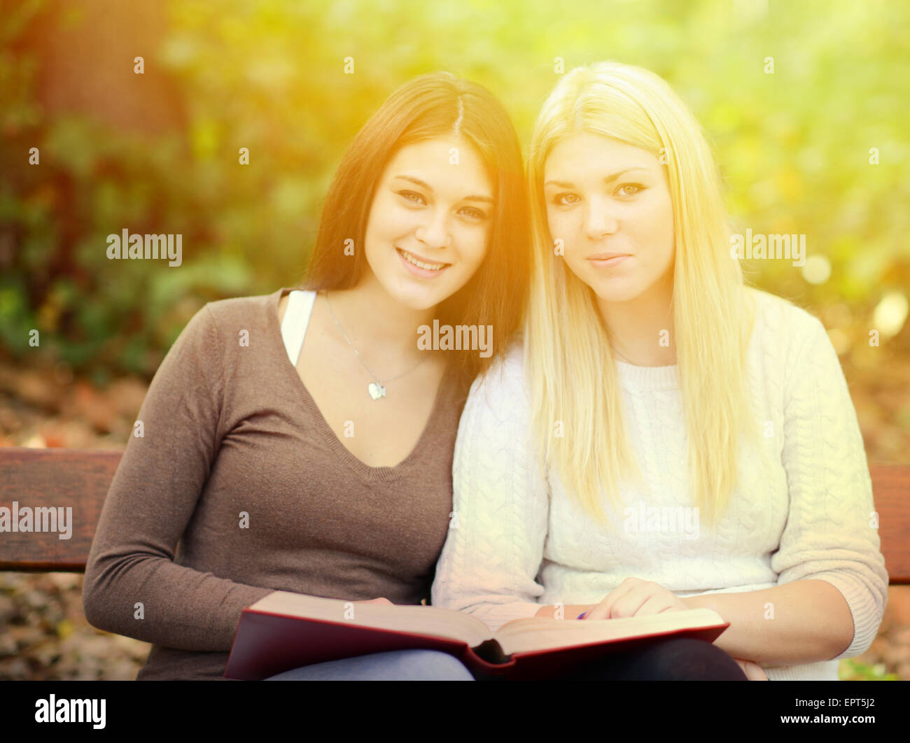 Two girls reading book in park Stock Photo - Alamy