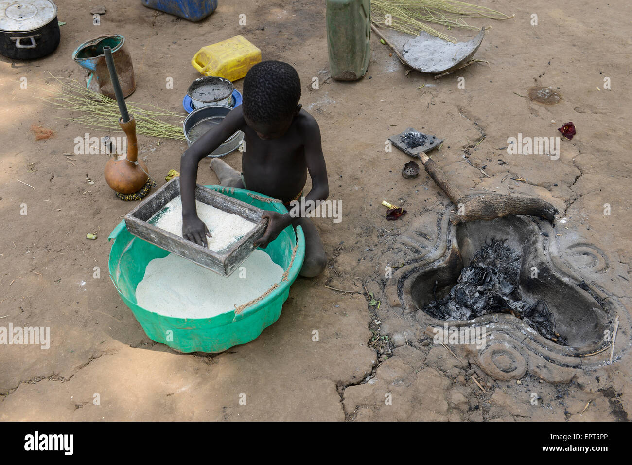 ETHIOPIA Gambela, village of Anuak tribe, boy sieve flour at cooking ...