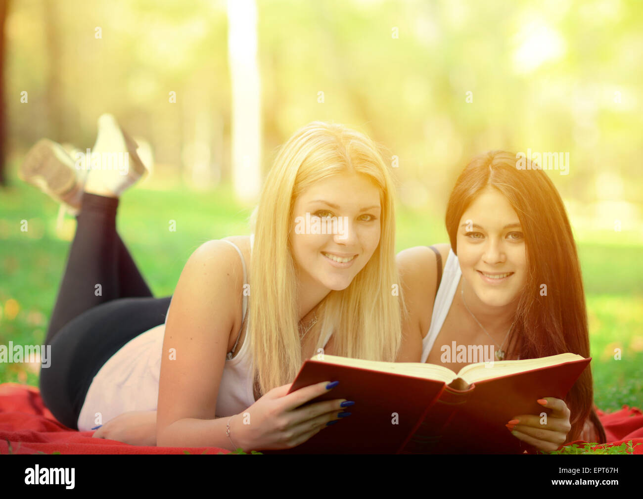 Two girls reading book in park Stock Photo - Alamy