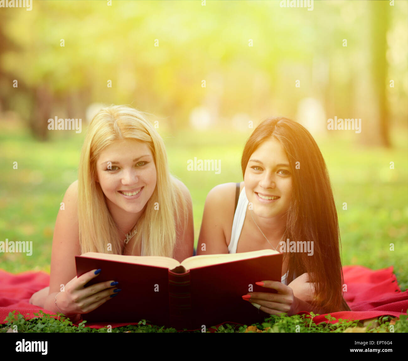 Two girls reading book in park Stock Photo - Alamy