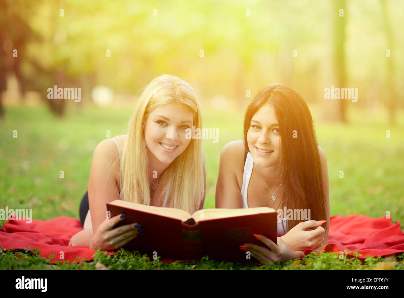 Two girls reading book in park Stock Photo - Alamy