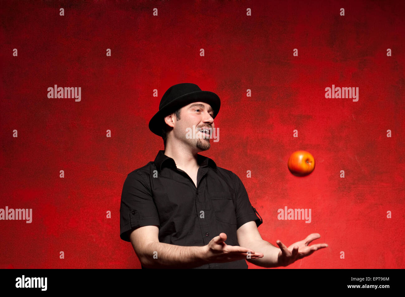 Young man juggling on a red background Stock Photo - Alamy