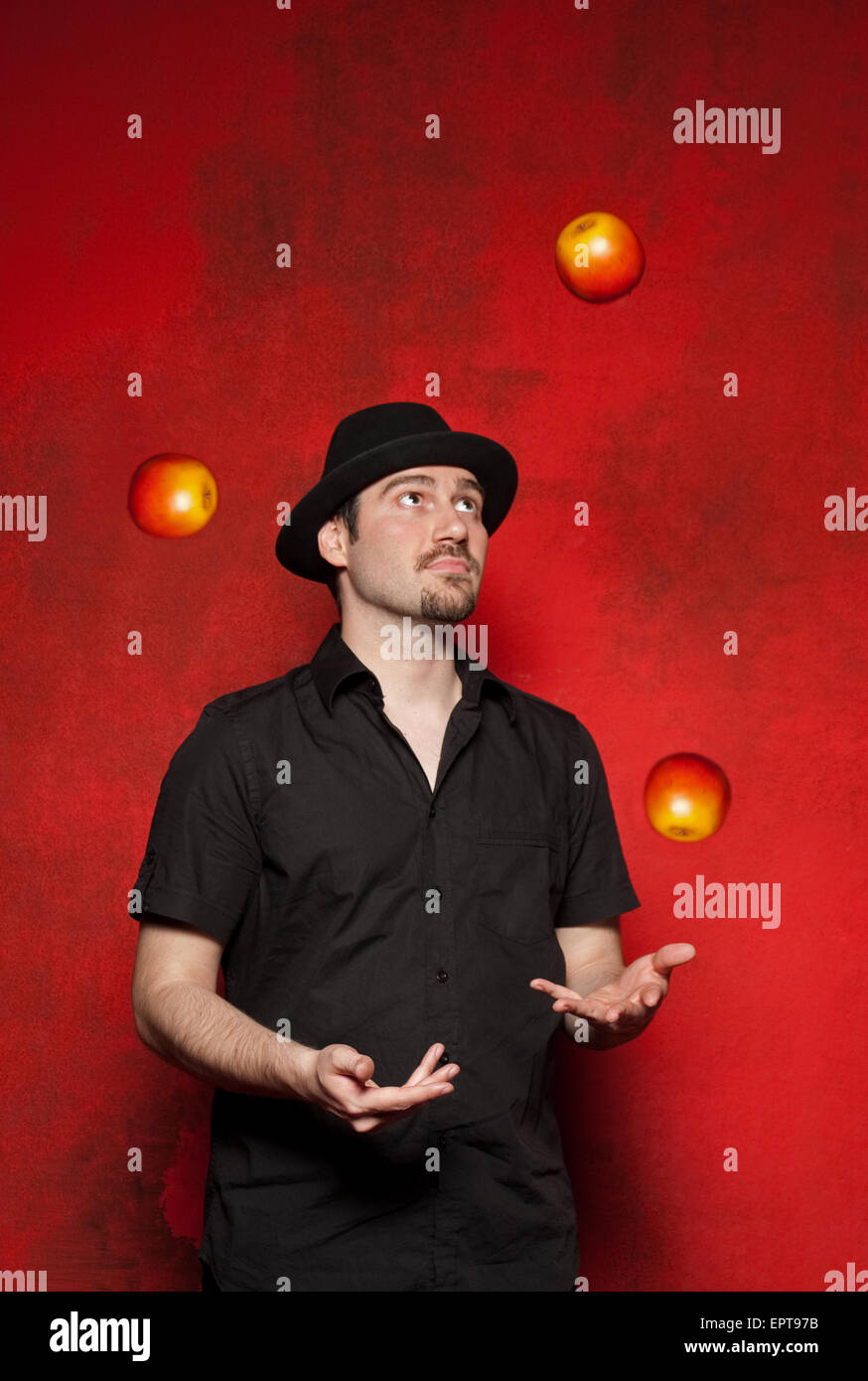 Young man juggling on a red background Stock Photo - Alamy