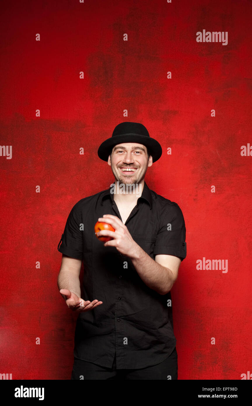 Young man juggling on a red background Stock Photo - Alamy