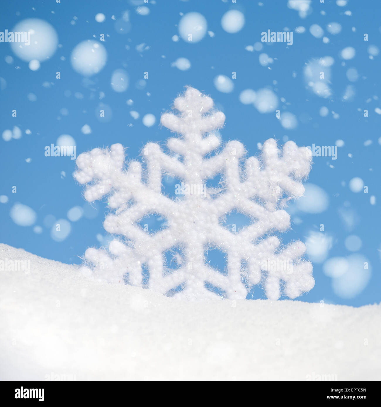 big snowflake toy with snowfall on blue sky background Stock Photo - Alamy