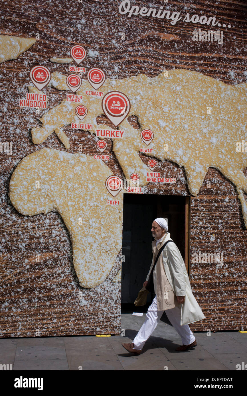 Man walks beneath a world map on a bakery business hoarding Stock Photo ...