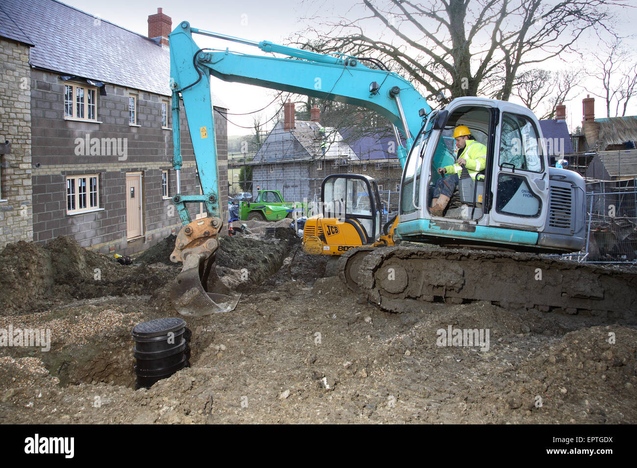 A construction worker uses an excavator to install the drainage system ...