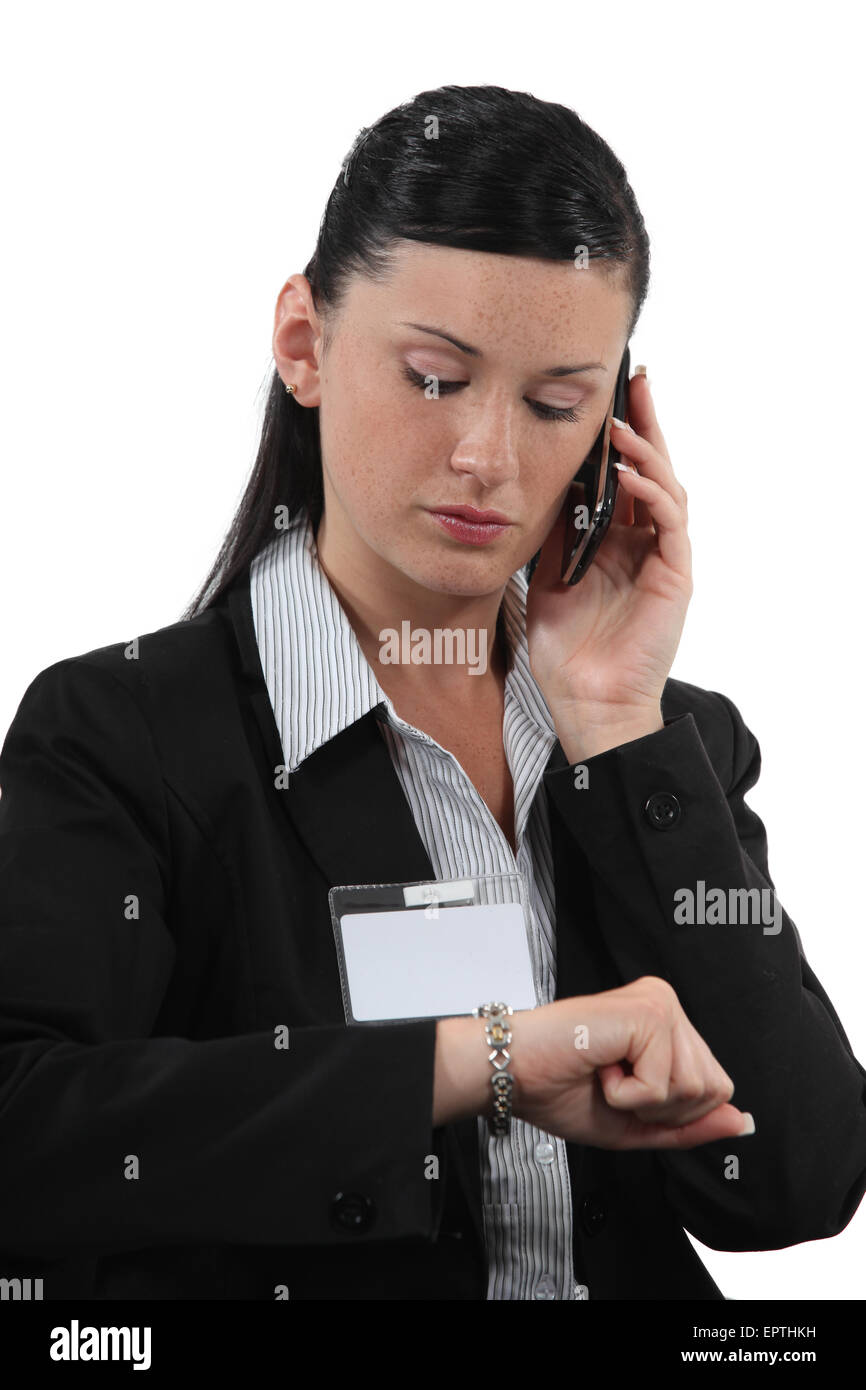 Female office worker making call and looking at watch Stock Photo - Alamy