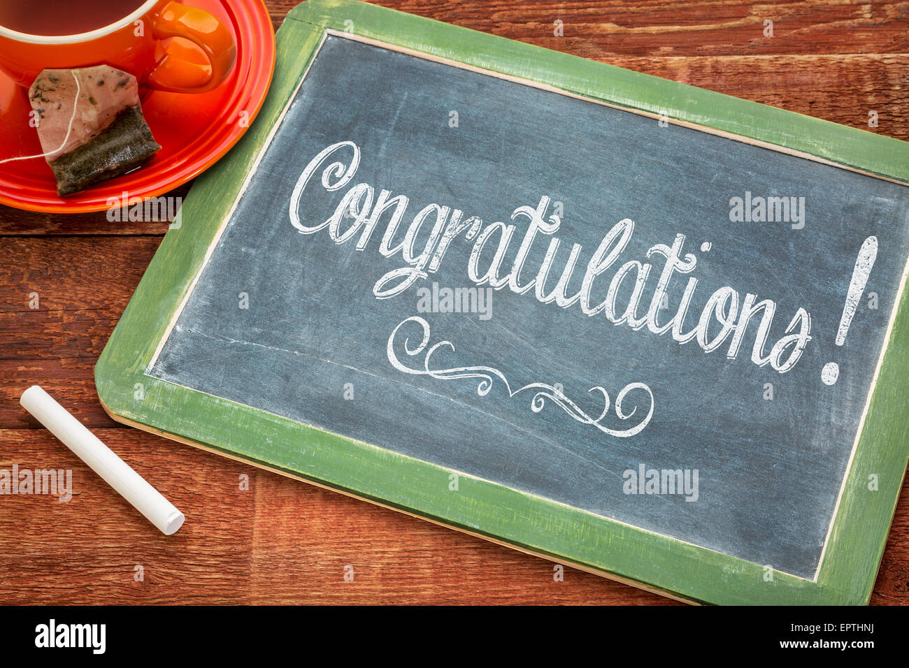 Congratulations! Text on a slate blackboard with chalk and cup of tea ...