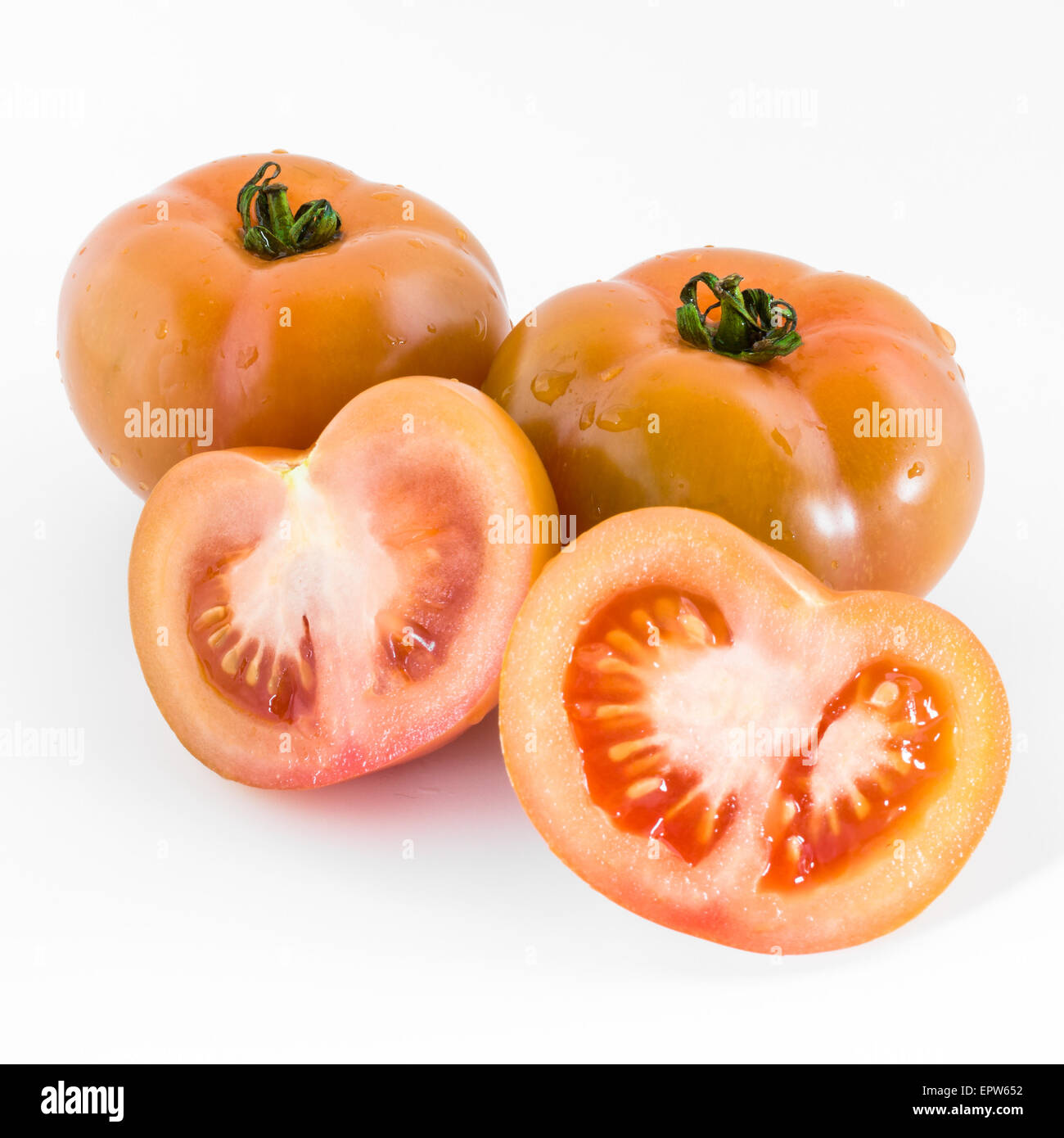 Two whole tomatoes and two halved Stock Photo - Alamy