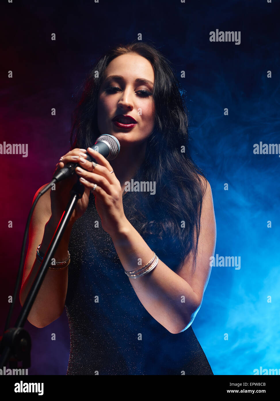 Beautiful woman sings, smoky stage on background Stock Photo - Alamy