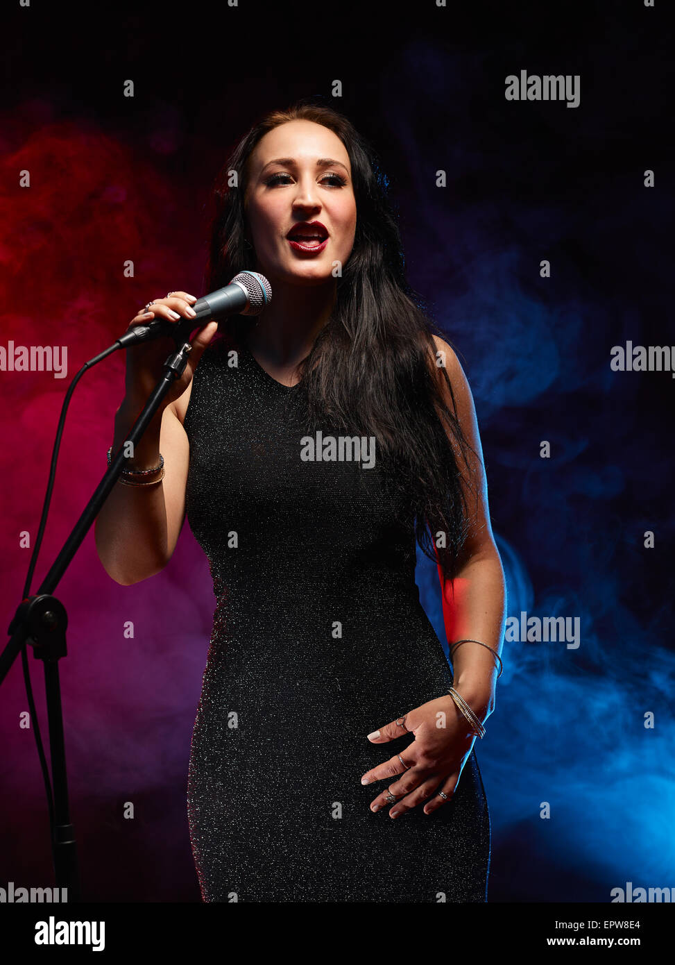 Beautiful woman sings, smoky stage on background Stock Photo - Alamy