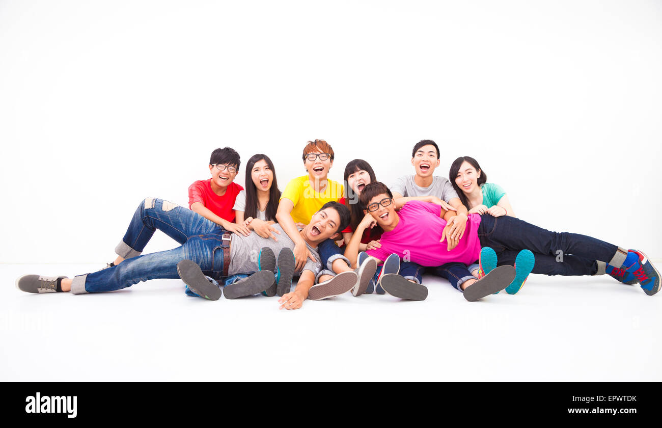Happy young group sitting together against white wall Stock Photo - Alamy