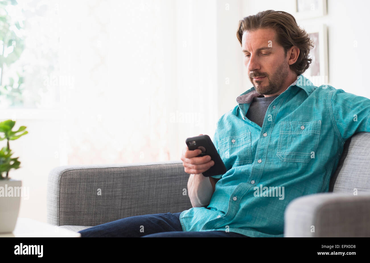 Man texting on sofa Stock Photo - Alamy