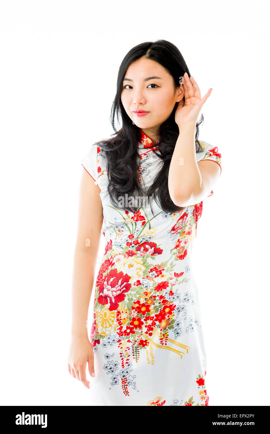 Asian young woman with hand to ear listening isolated over white ...