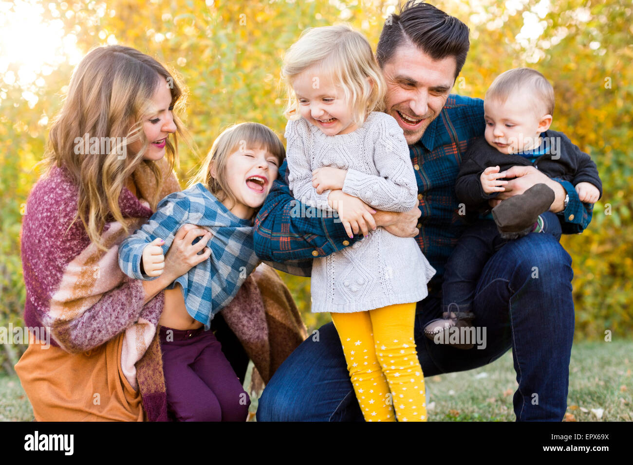 Happy family with tree children (6-11 months, 2-3, 4-5) playing in park ...