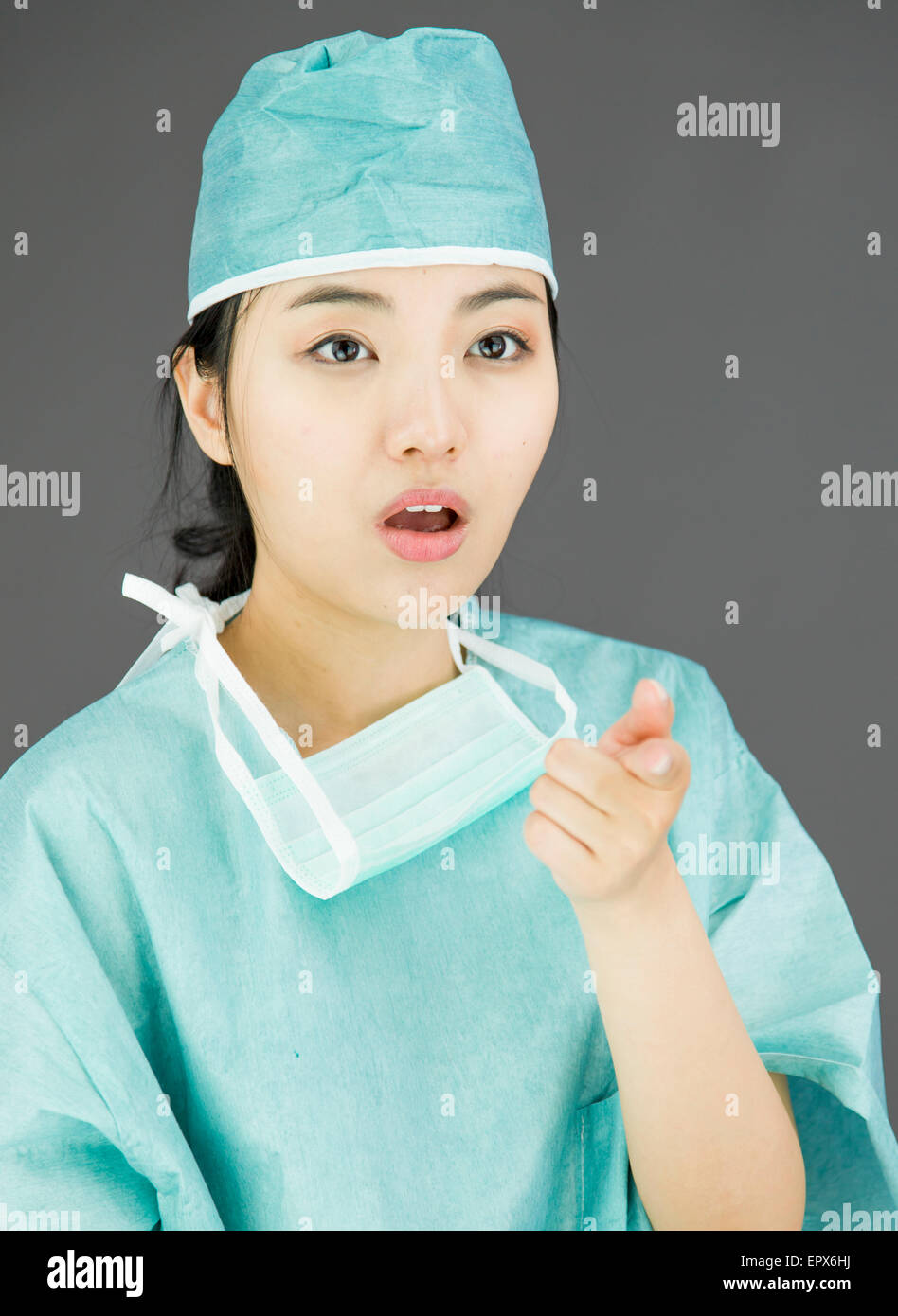 Shocked Asian female surgeon with pointing isolated on colored ...