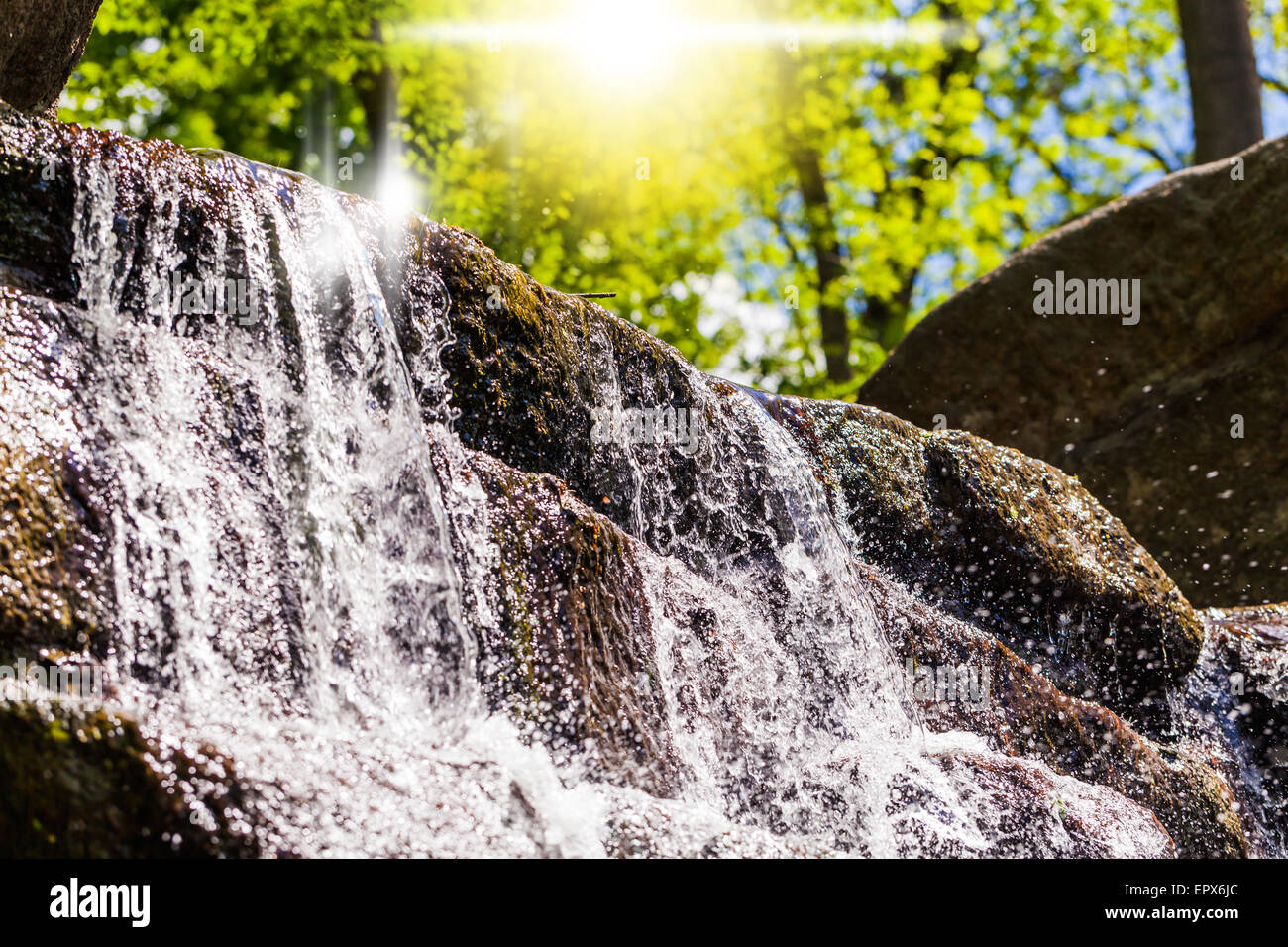 stream of water flowing along the a rock on a background greenery Stock ...