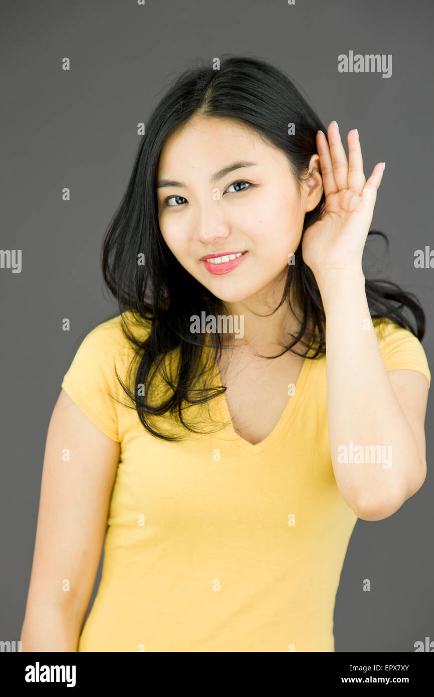 Asian young woman with hand to ear listening Stock Photo - Alamy