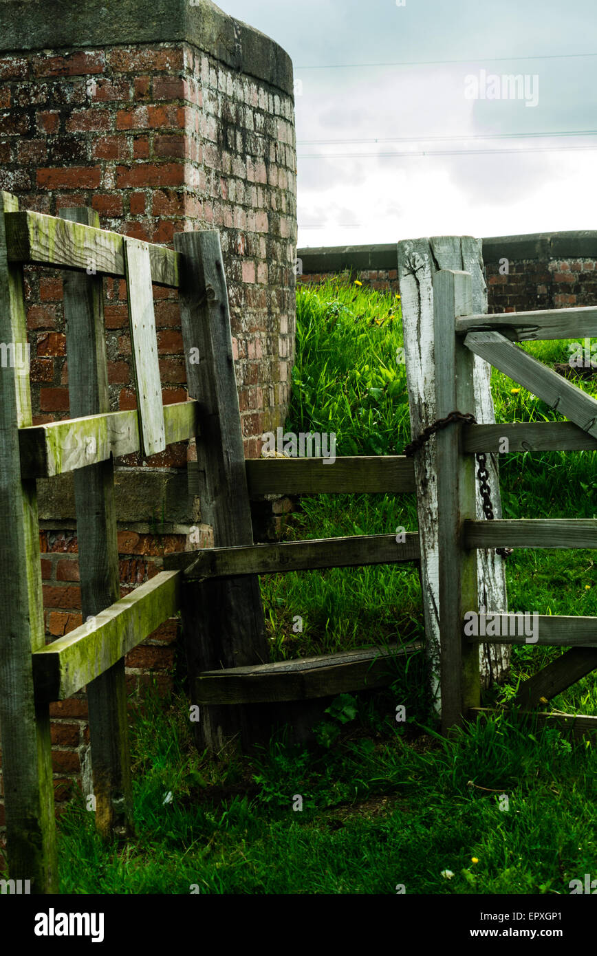 Vertical image of wooden stile and gate next to a brick-built road ...