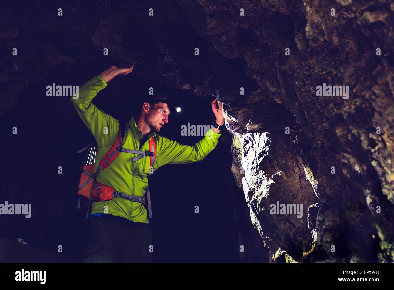 Man walking and exploring dark cave with light headlamp underground ...