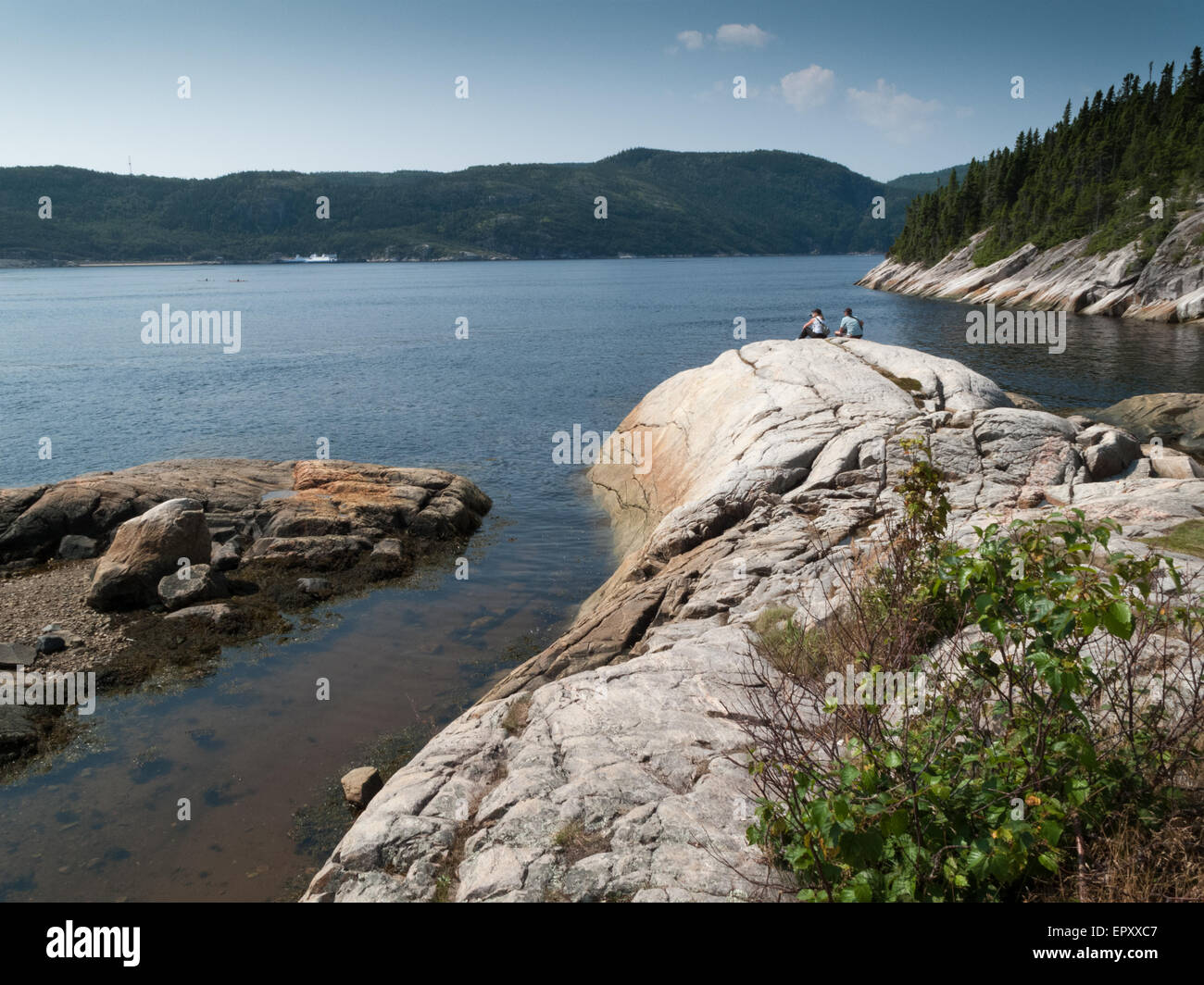 Two tourist sitting on rock at the riverside, Saint Lawrence River ...