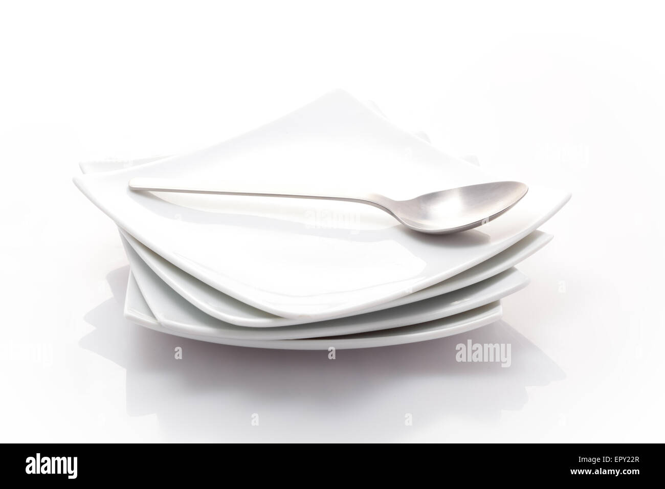 stack of square plates with a spoon isolated on a white background ...
