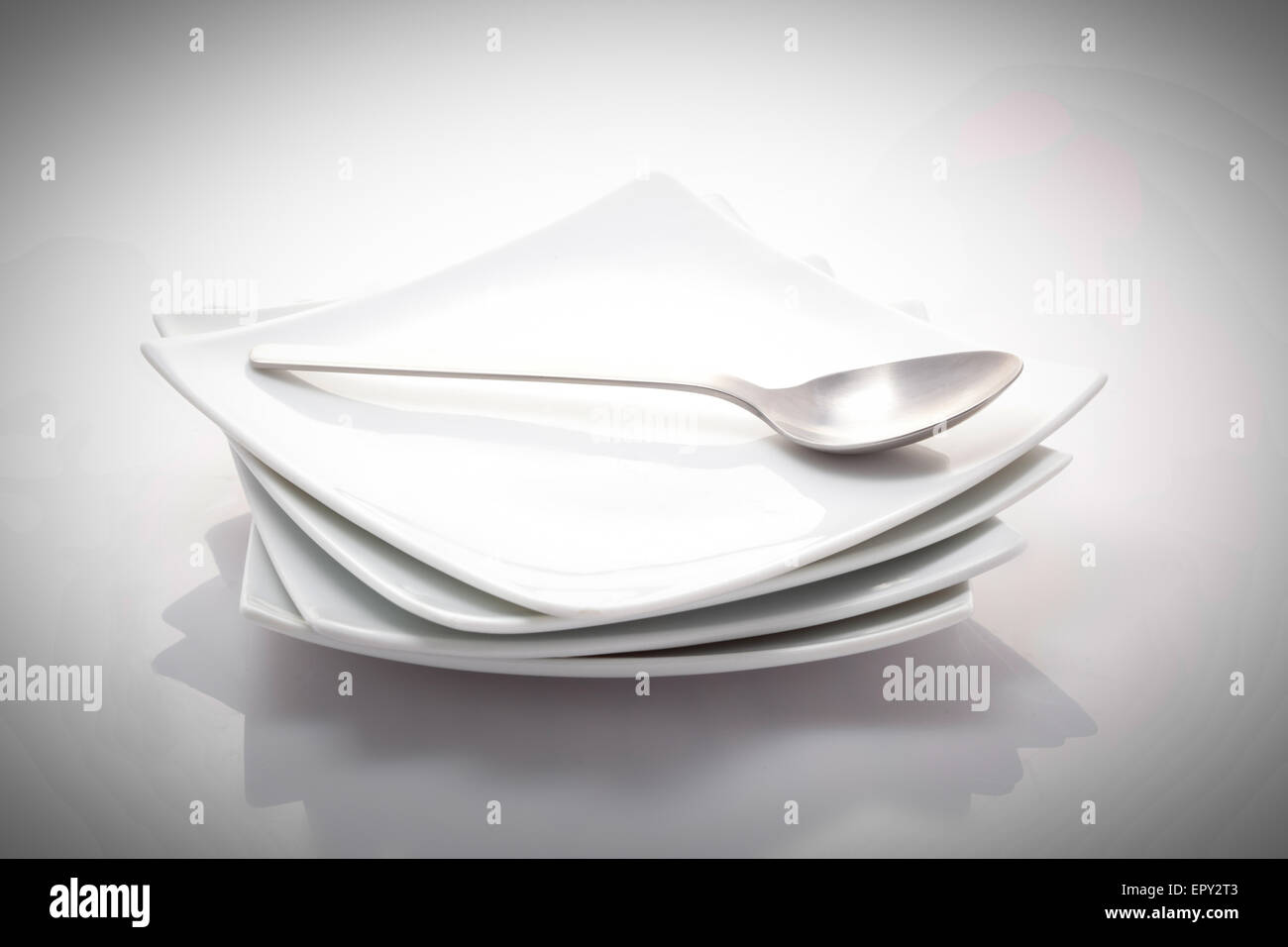 stack of square plates with a spoon isolated on a white background ...