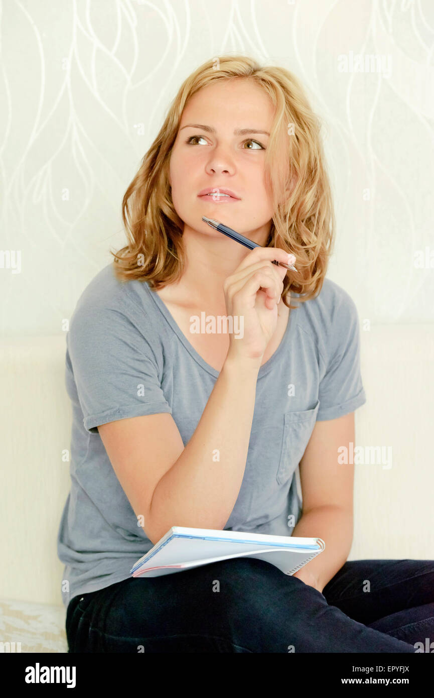 Young woman thinking over making notes in notebook Stock Photo - Alamy