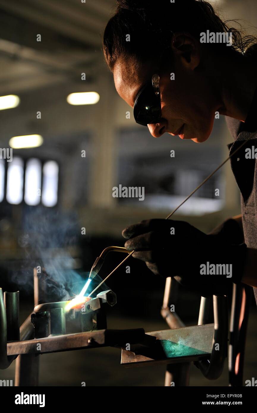 Female welder holding welding torch; woman welder welds a piece of ...